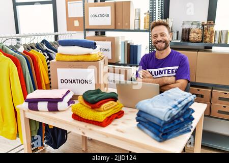 Middle age man wearing volunteer t shirt at donations stand smiling ...