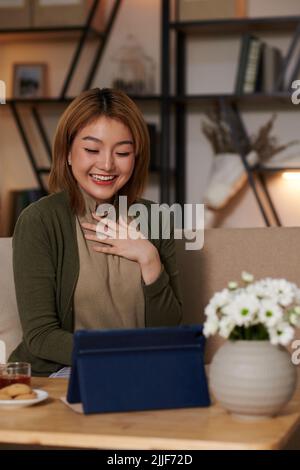 Young Asian woman enjoying video game break while working from home ...