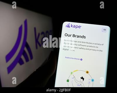 Person holding cellphone with webpage of cybersecurity company ...