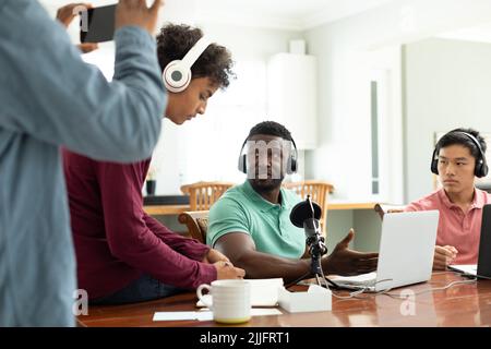 Midsection of man filming multiracial male coworkers recording podcast ...