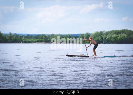 Sap surfing. Surf training. Men, friends ride SUP boards on a big river ...