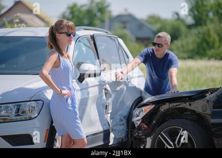 Angry woman and man drivers of heavily damaged vehicles arguing who is ...