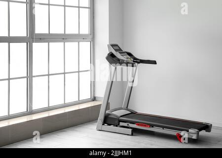 Modern treadmill near window in gym, closeup Stock Photo - Alamy