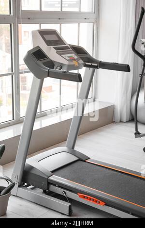 Modern treadmill near window in gym, closeup Stock Photo - Alamy