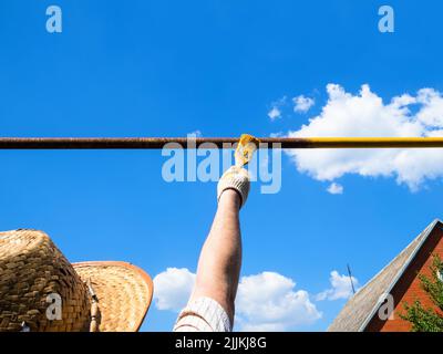 hand paints rusty outdoor gas pipe with yellow paint using brush and ...