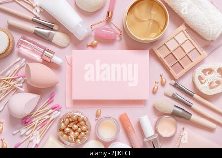 Paper card between skin care and decorative cosmetics on pink, top view ...