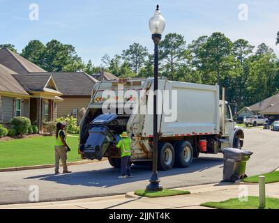 Garbage truck and garbage men picking up the trash in a residential ...