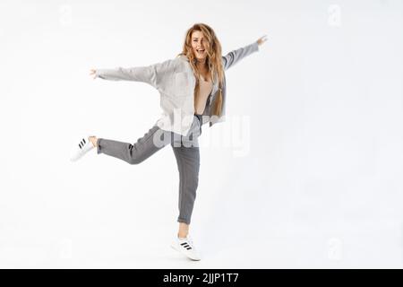 The woman emotionally jumps up, arms outstretched and leg raised ...