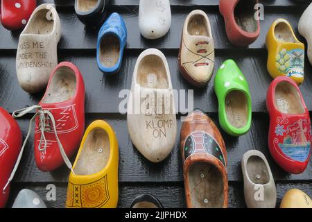 A closeup of multiple clogs in different colors on the wall with ...