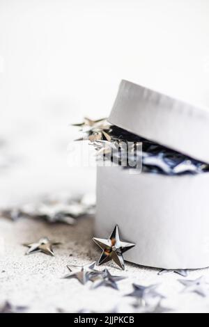 Silver star decorations spilling out of a box on a table Stock Photo ...