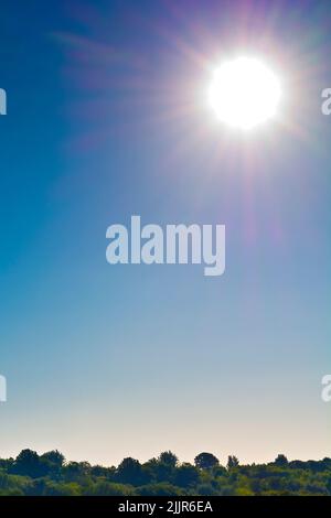 Sun with sun rays in cloudless sky over a snow field below the summits ...