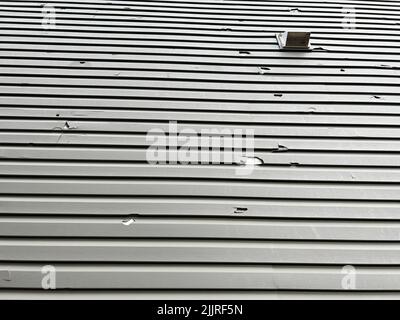 Holes in the exterior siding of the home from hail storm damage. The ...