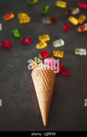 A vertical closeup shot of an ice cream cone filled with gummy bears ...