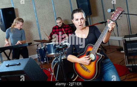 Attractive female soloist playing guitar and singing with her mu Stock ...