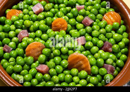 Green peas with serrano ham and carrot on wooden table Stock Photo - Alamy