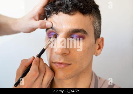 Caucasian transgender man getting makeup done by his boyfriend at home ...