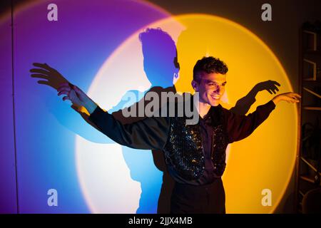 Transgender male standing arms outstretched performing in illuminated ...