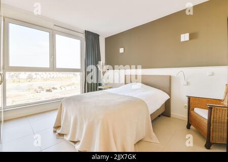 Comfortable bed next to a bright window and wooden floor Stock Photo ...