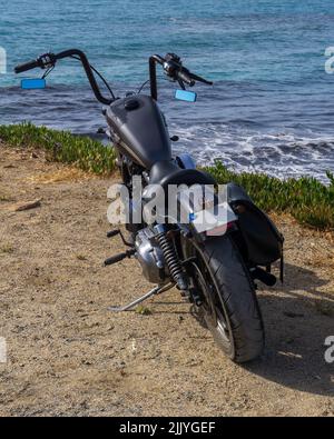 A black classic motorcycle stands on a cliff above the ocean Stock ...