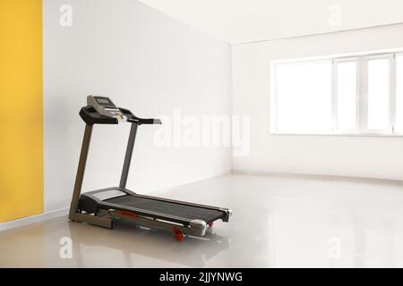 Modern treadmill near yellow and white wall Stock Photo - Alamy