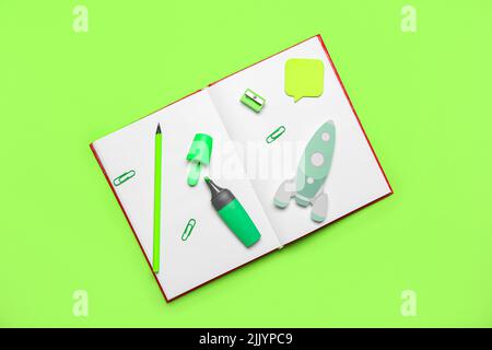 Paper rocket with notebook and school stationery on green background ...