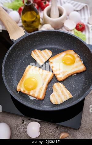 Fried egg Toasts with heart shaped holes on frying pan Stock Photo - Alamy