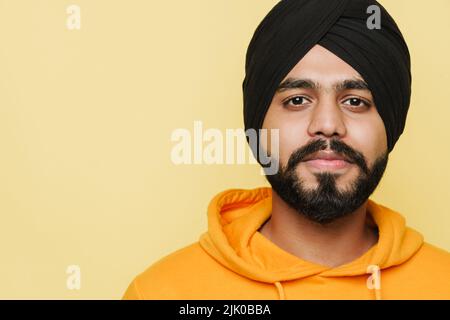 South asian man wearing turban and face mask looking at camera isolated ...