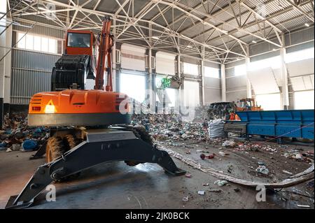 Excavator grabs trash in warehouse of waste processing plant Stock ...