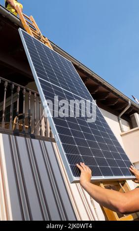 worker lifting solar panel up ladder to rooftop. Navarre, Spain, Europe ...
