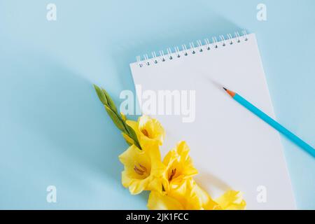 Beautiful yellow Gladiolus flower and a notebook with blank page on a ...