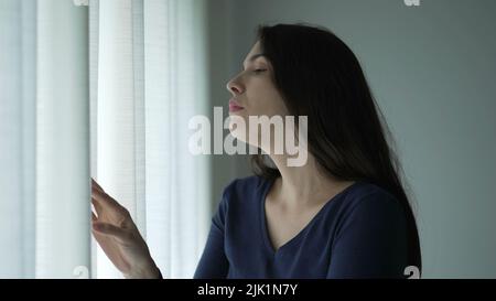 One careful female standing by window peeking out surveillance ...