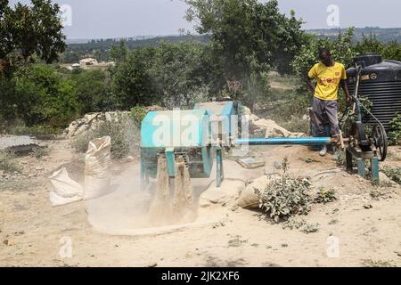 An artisanal miner operates an ore-processing machine used to separate ...