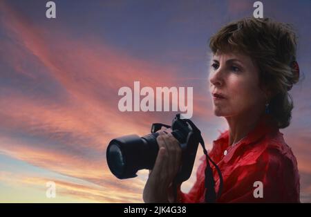 Woman with short red hair is shooting on vintage film camera ...