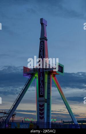 A Pendulum ride roller coaster lit up with multi color light bulbs at ...