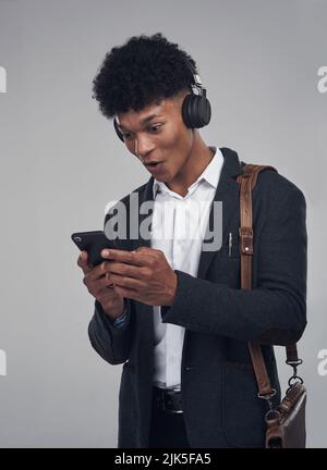 Excited grey man using mobile phone while working with computer in ...