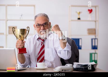 Old businessman employee being awarded with golden cup Stock Photo - Alamy