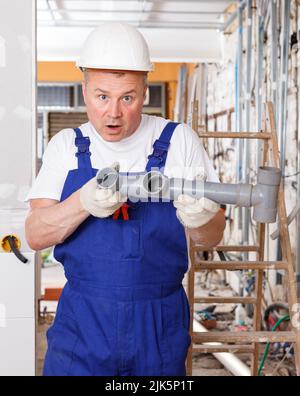 Puzzled builder with plastic pipes Stock Photo - Alamy
