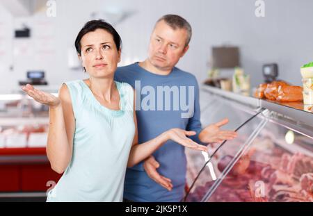 Sad couple customers choosing meat in butcher’s shop Stock Photo - Alamy