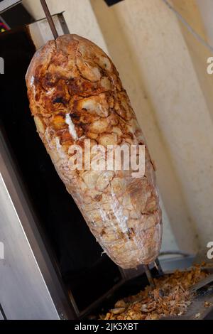 Traditional doner kebab with stacked pork grilling on a rotisserie in ...