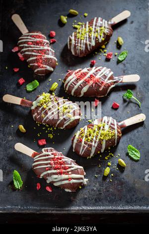 Homemade and cold popsicles looking like small ice cream on dark stone ...