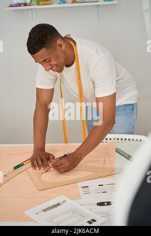 African American man tailor draw dress pattern of product on paper ...