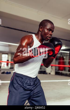 Focused athlete in boxing gloves working on punching technique and ...