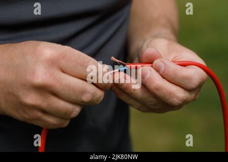 Severed power cable held in a mans hands and fingers, ready to be ...