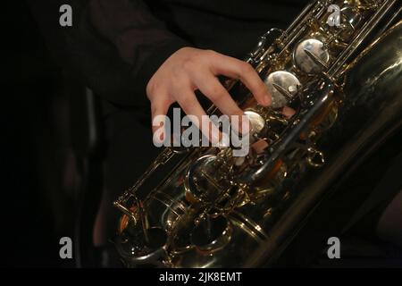A closeup of the hands of a musician playing a baritone saxophone Stock ...