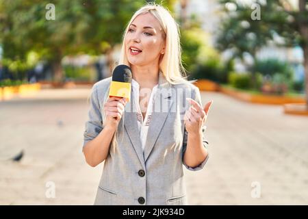 Young blonde woman reporter working using microphone at street Stock ...