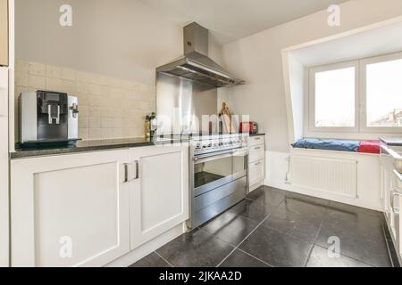 Contemporary cupboards with appliances and tables with kitchenware ...