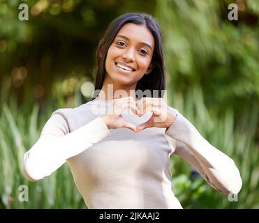 Lets spread the love. a beautiful young woman forming a heart shape ...
