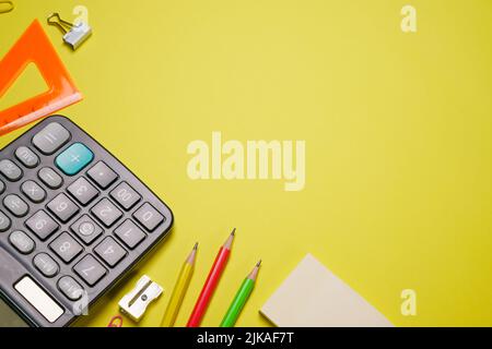 Calculator and stationery in different colors on a yellow background ...