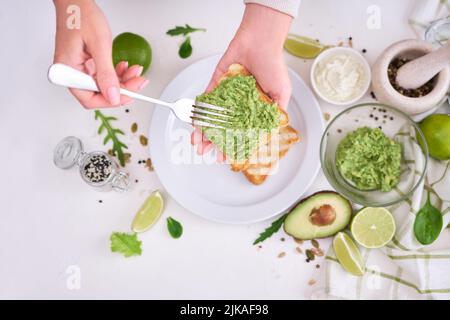 Toasts preparation - woman smearing mashed avocado on a toasted bread ...