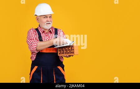 smiling old aged man bricklayer in helmet on yellow background Stock ...